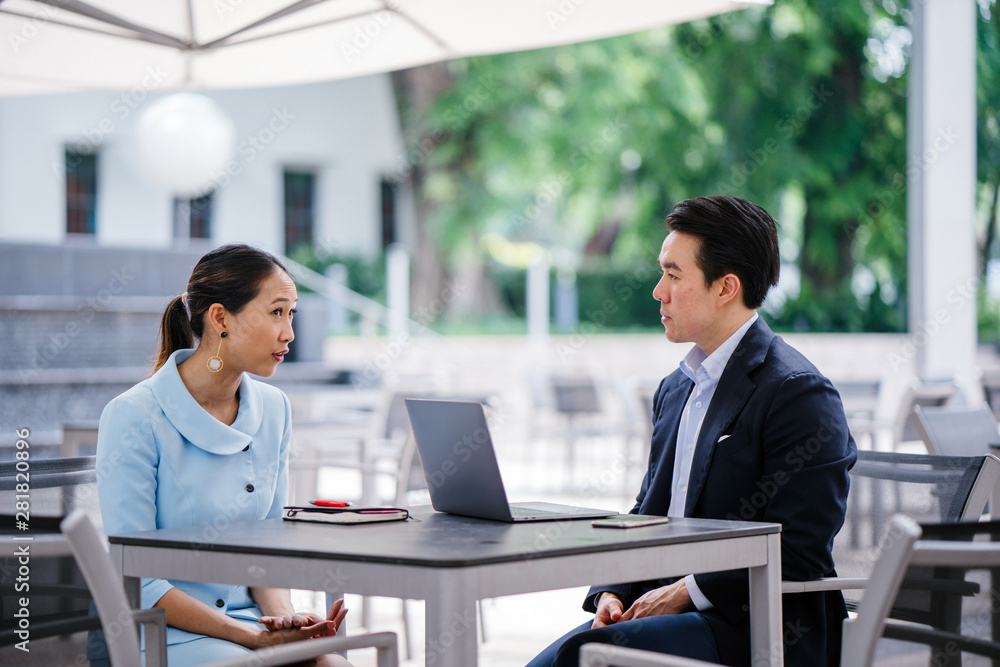 A Chinese Asian manager in a suit has a meeting with his colleague, a ...