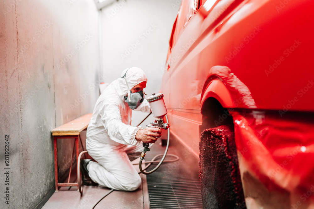 Mechanic working on painting a red car in special booth Stock Photo ...
