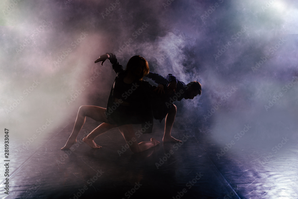 Modern dance couple twisting their legs and lening close to the ground ...
