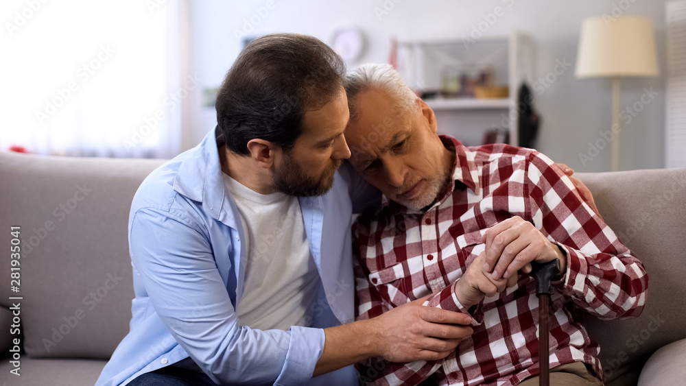 Sad son calming disabled senior father, health problems, suffering ...