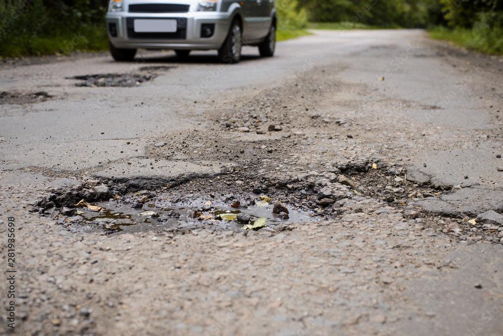 Damaged asphalt pavement road with many big and deep potholes. Concept ...