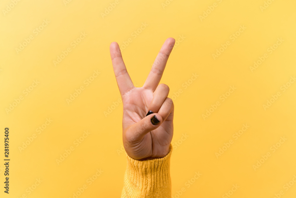 Hand gesture V sign for victory or peace sign over yellow background ...
