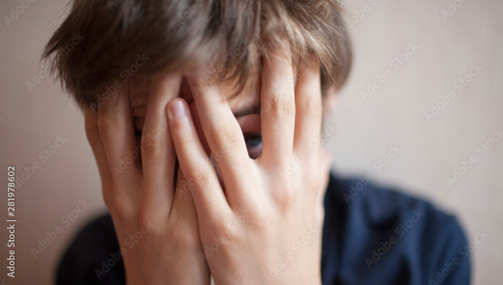 Teen boy covers his face with his hands Stock Photo | Adobe Stock
