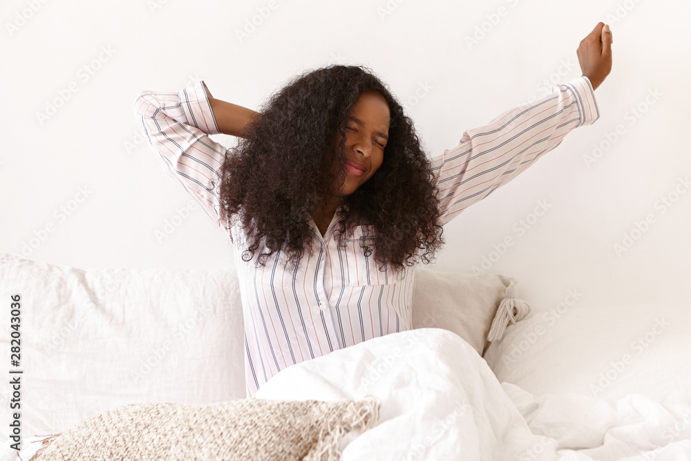 Sleepy pretty girl with brown skin and voluminous hairdo stretching ...