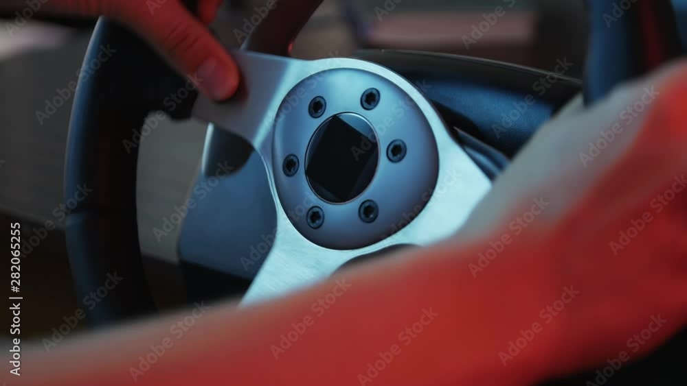 Close-up of the hands of a young gamer behind the steering wheel of a ...