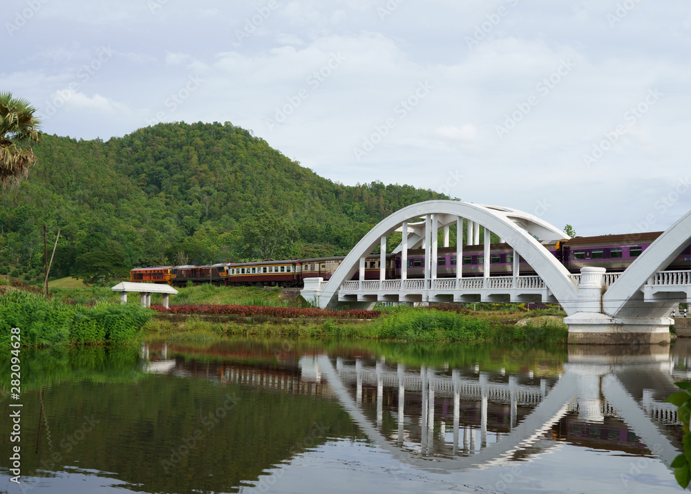 Diesel Train passing the Tha Chom Phu railway bridge or white bridge ...