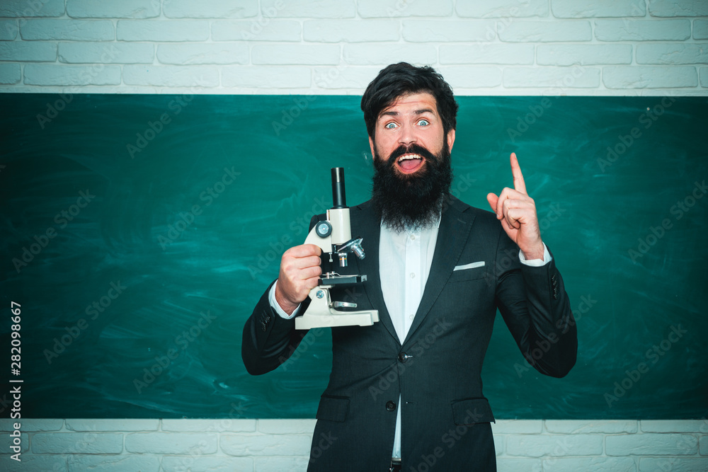 Serious male Student studying in school. Young bearded teacher near ...