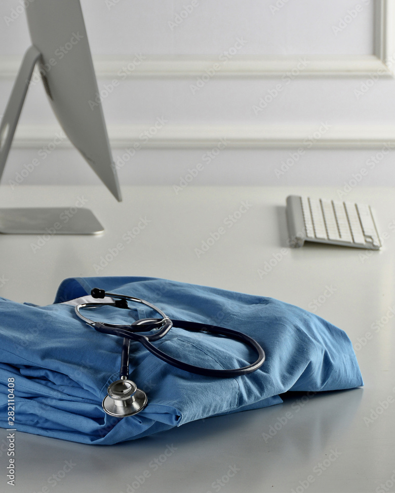 Medical stethoscope head lying on a blue doctor uniform in a hospital ...