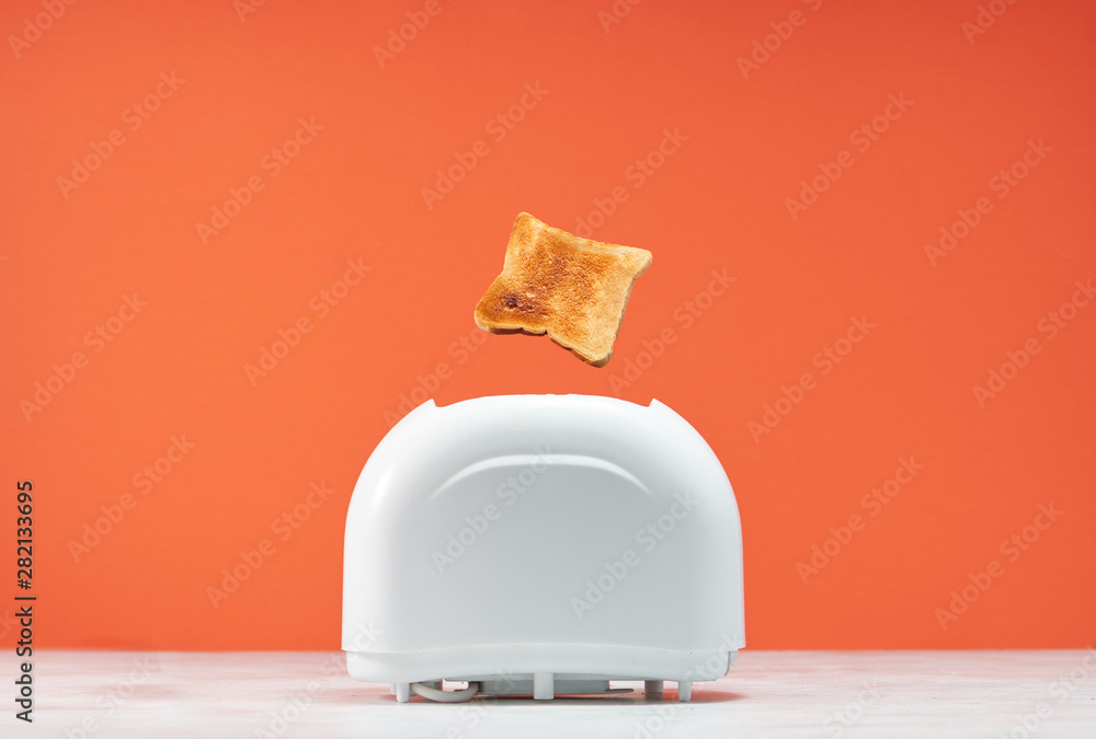 Roasted toast bread popping up of toaster with blue wall, front view ...