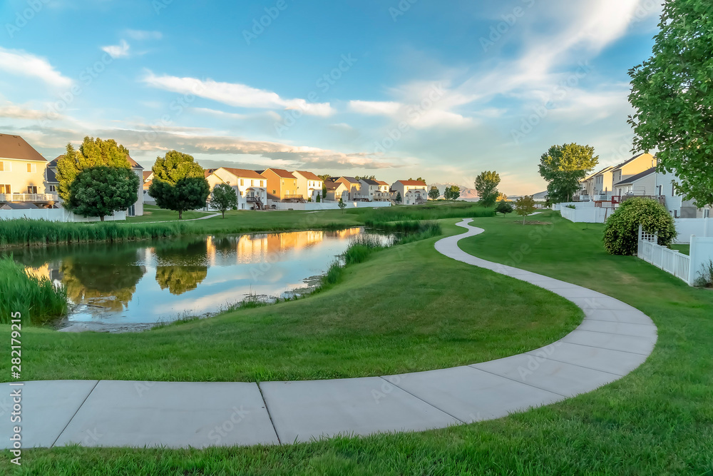 Homes overlooking a grassy park with shiny pond and winding pathway ...