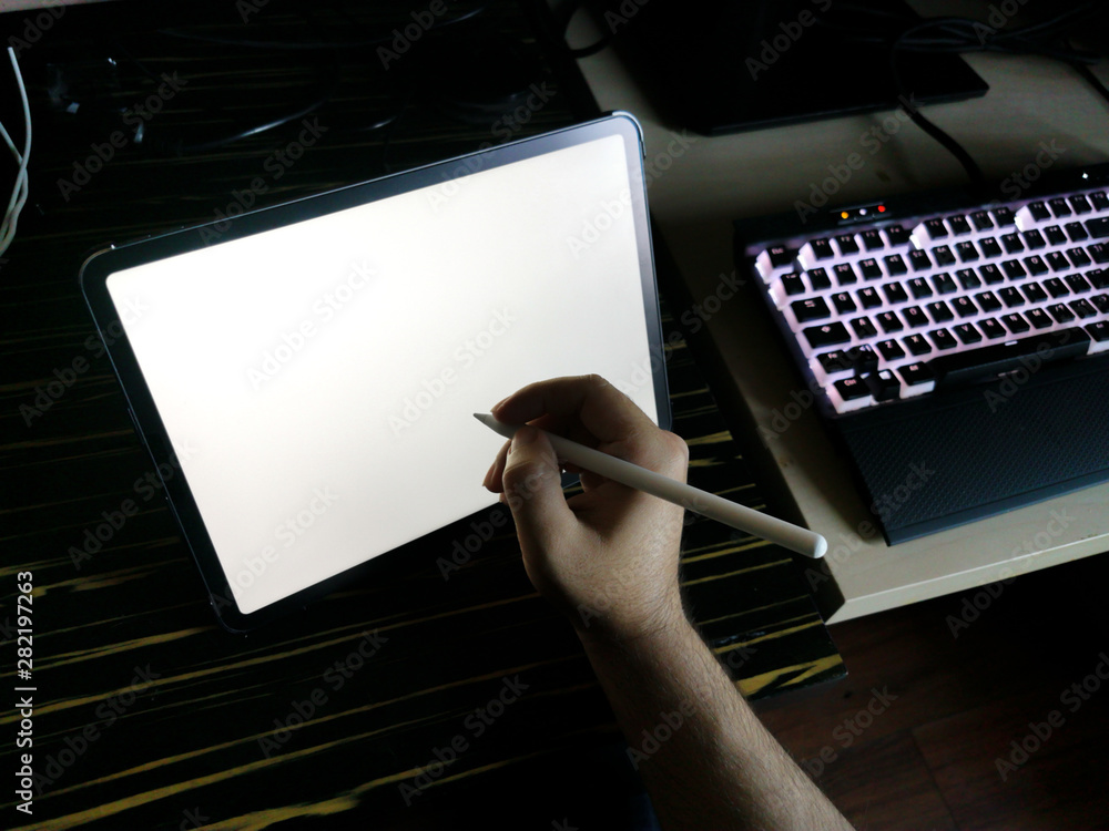 male hand drawing illustration on pro tablet next to gaming workstation ...
