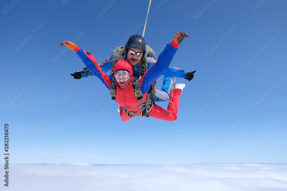 Skydiving. Tandem jump. A strong man and a young woman are falling in ...