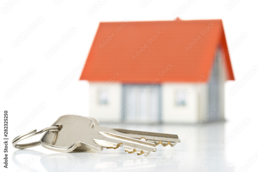 House keys in front of model house over white background - home owner ...