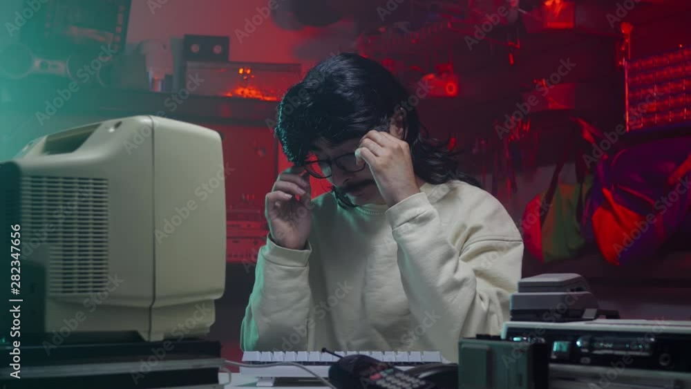 In the '80s or '90s young man being tired using his personal computer ...