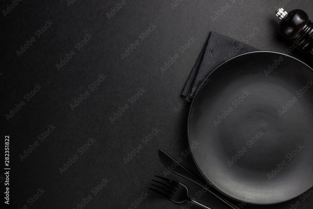 Black setting: plates, linen napkin and silverware on blfck background ...