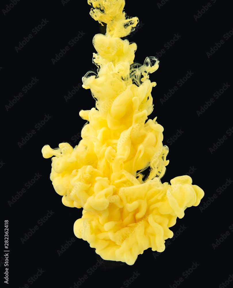 Droplet of yellow paint makes an abstract swirl under water, isolated ...