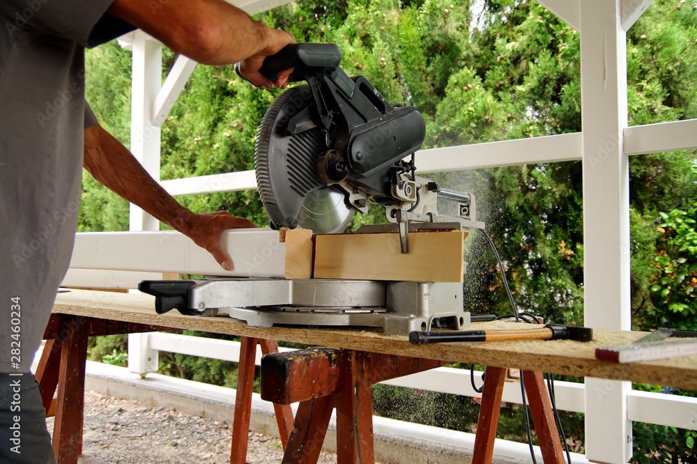 carpenter using a circular saw to cut a wooden beam. Woodworking and ...