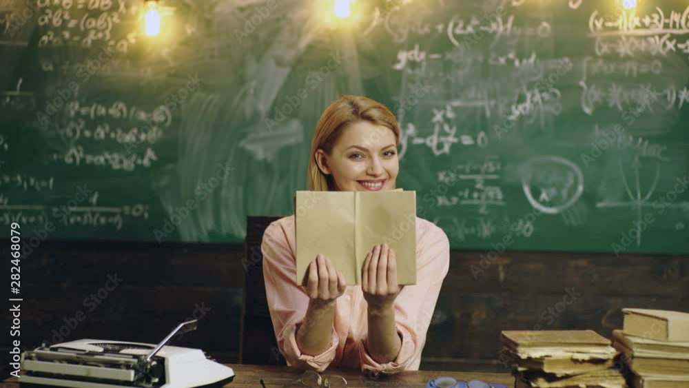 Woman smiling. Female teacher holding book in her hands and smiling on ...
