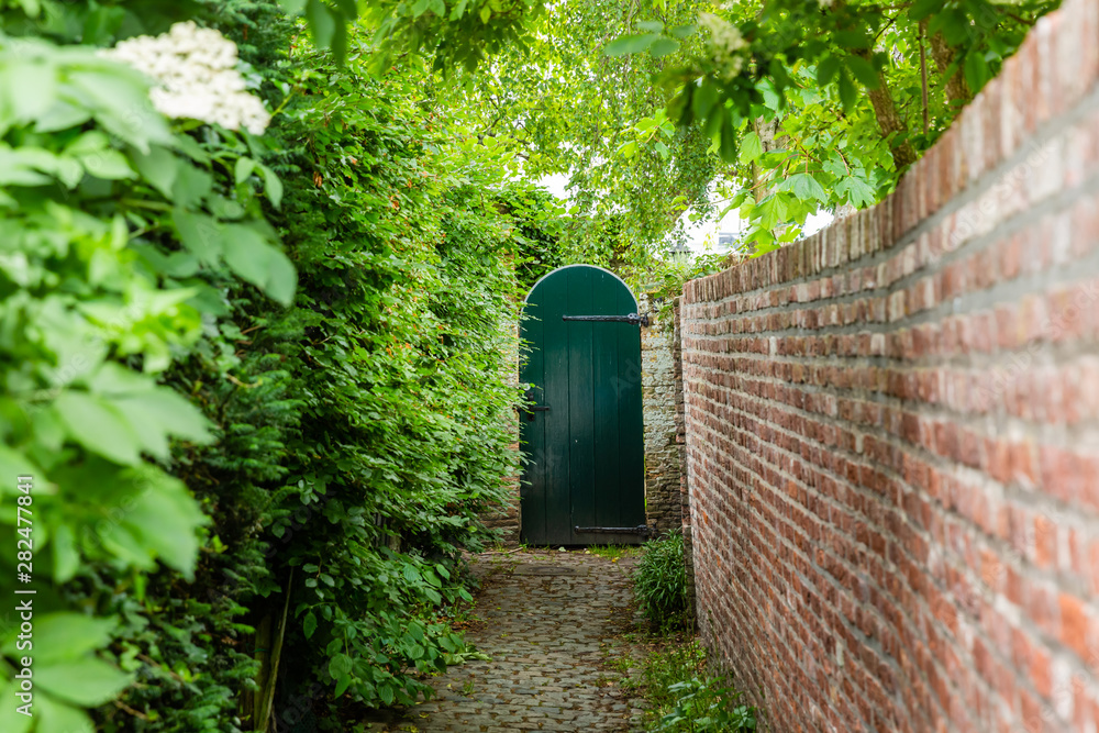 narrow access path to a wooden garden gate Stock Photo | Adobe Stock