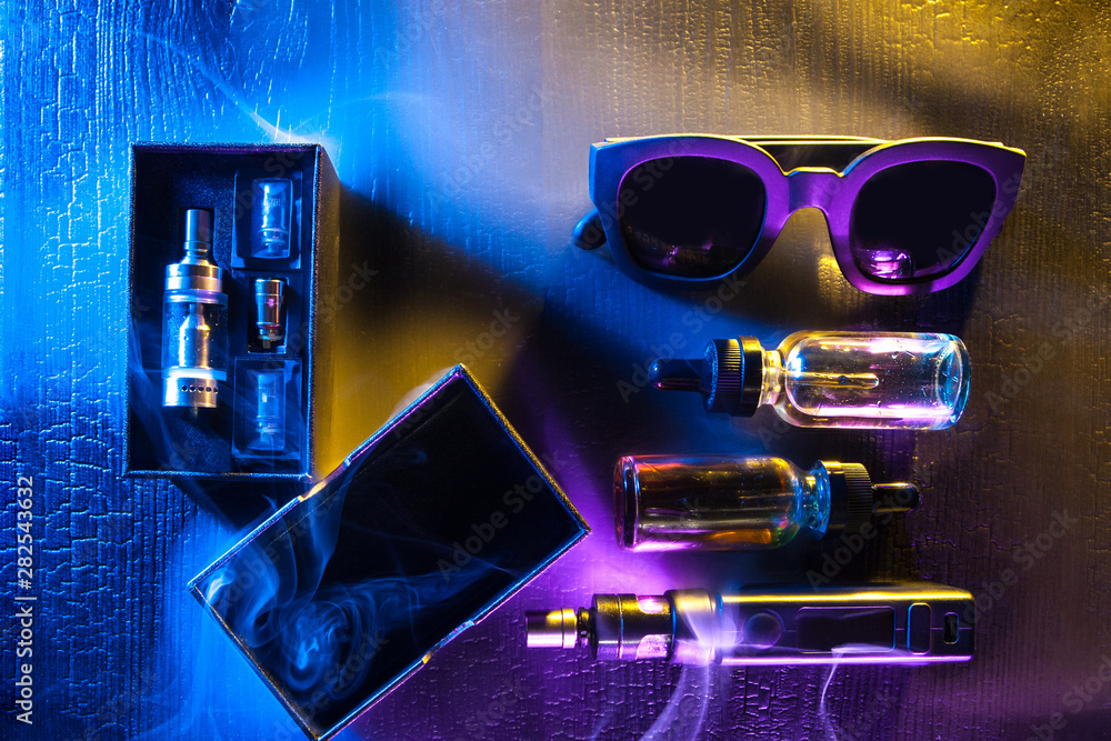 The vaping concept. Electronic cigarette and accessories on colorful ...