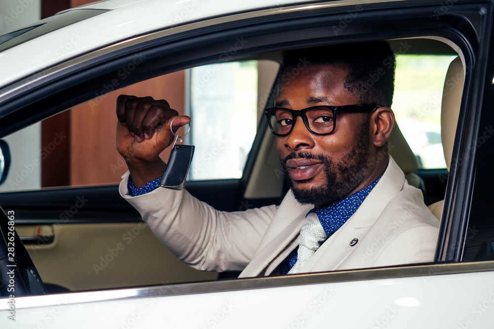 Foto de Handsome black man is holding key of his new car and smiling do ...