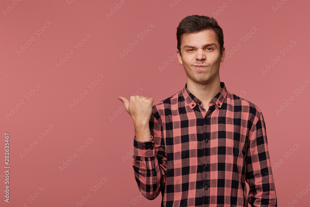 Frowning frowning man wears in checkered shirt, looks at the camera ...