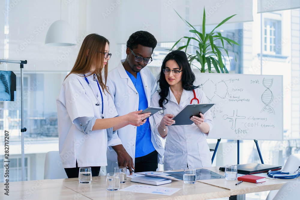 Group of three international doctors discussing lungs xray of the ...