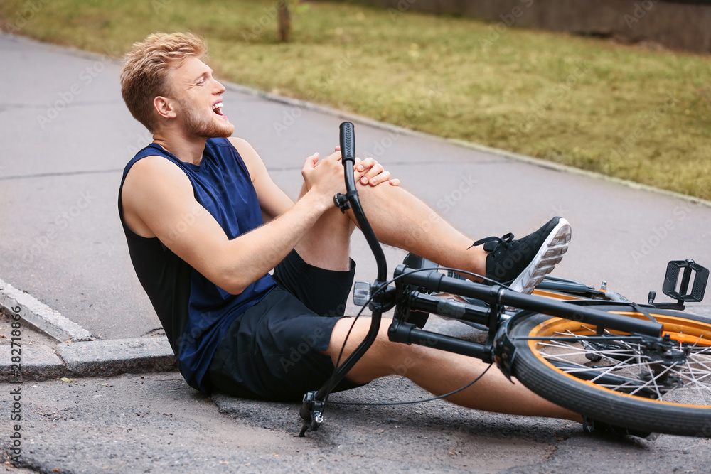Sporty young man fallen off his bicycle outdoors Stock Photo | Adobe Stock