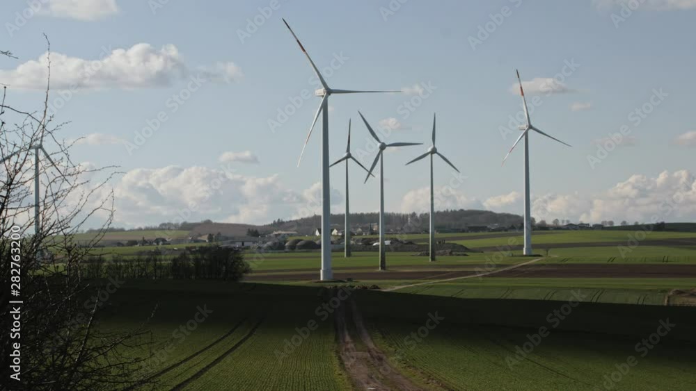 wind turbines spinning on a field with path leading to village in ...