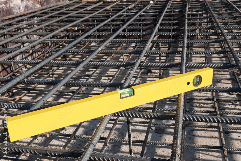 Building yellow colored level tool on the steel grid of residential ...