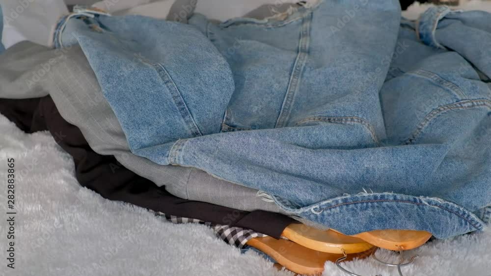 Close-up shooting of clothes that are thrown on the bed. Woman wardrobe ...