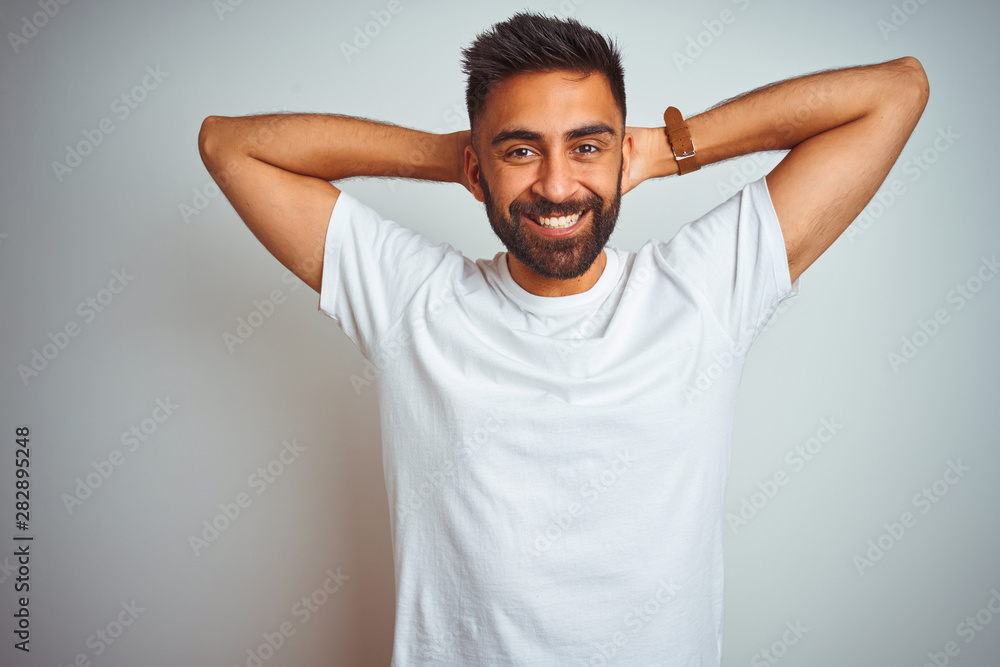 Young indian man wearing t-shirt standing over isolated white ...