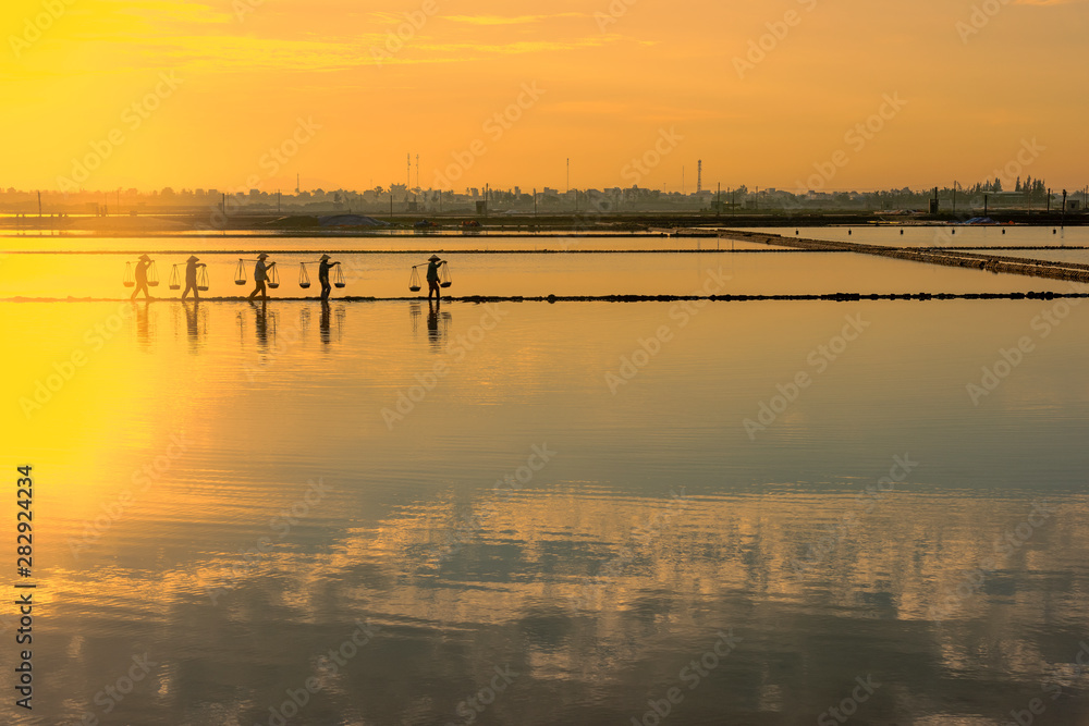 Woman carrying baskets of freshly harvested salt on their shoulders at ...