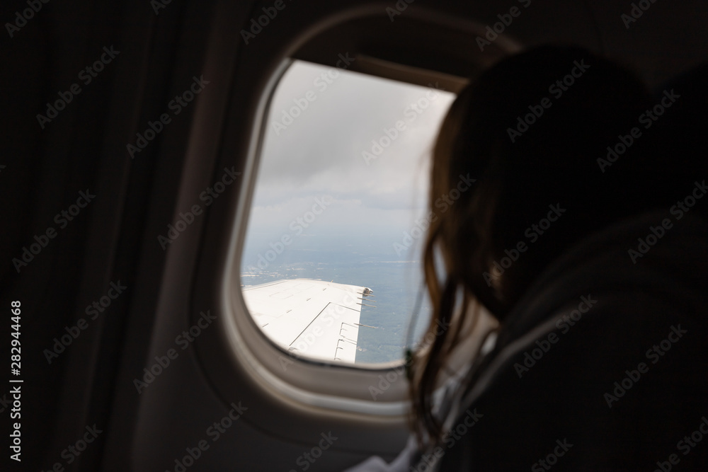 Girl looking out window of airplane in flight Stock Photo | Adobe Stock