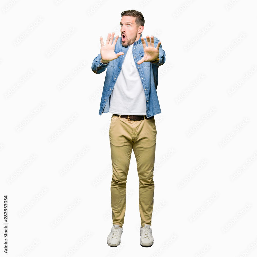 Handsome man with blue eyes and beard wearing denim jacket afraid and ...