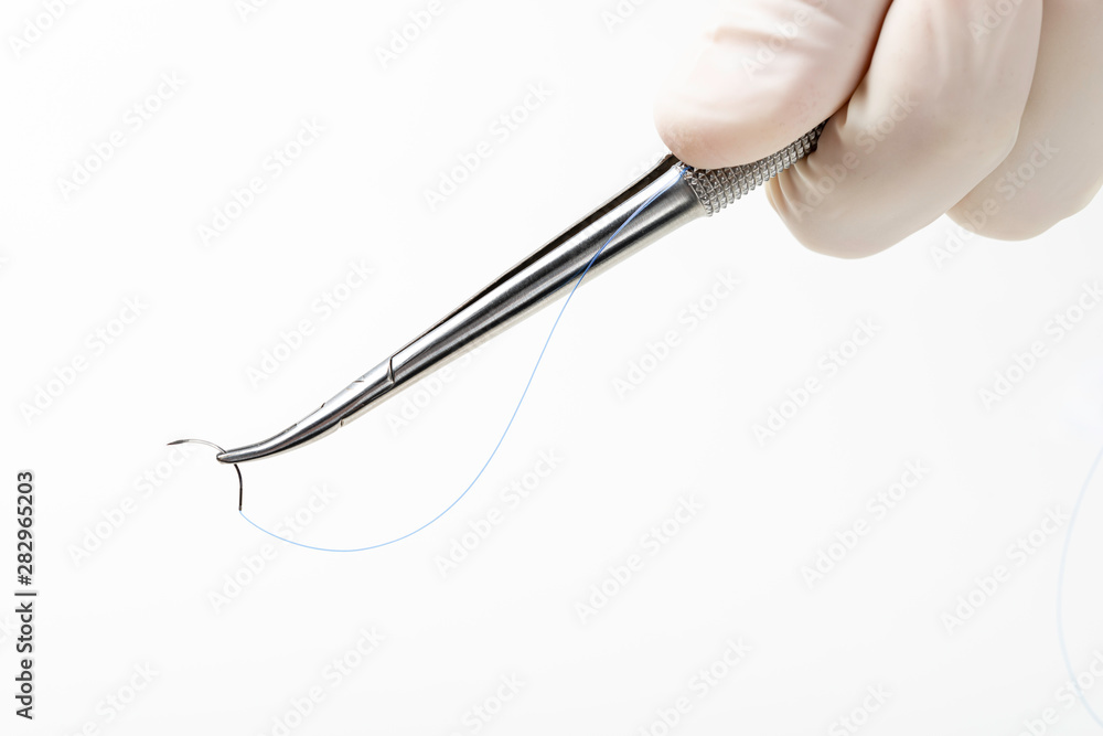 Doctor holding needle holder on white background. Suture thread. Nylon ...