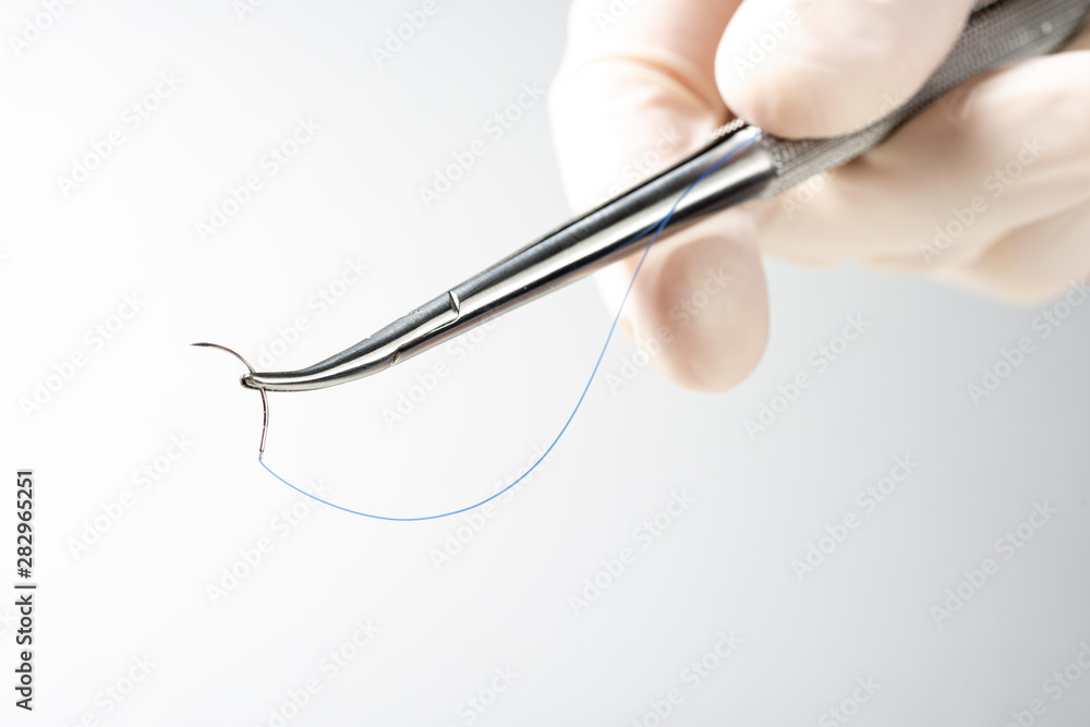Doctor holding needle holder on white background. Suture thread. Nylon ...