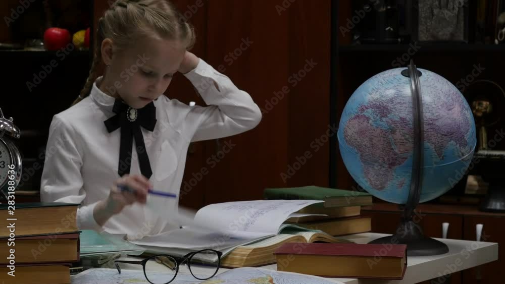 Schoolgirl doing homework, little blonde girl studing at home at the ...