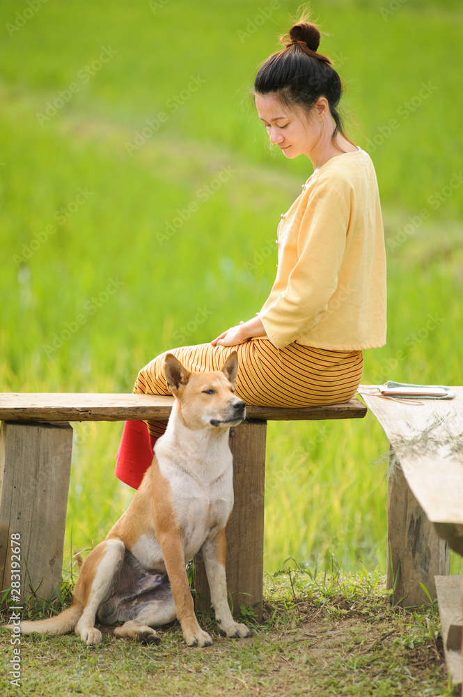 asian woman sit on wooden chair and her dog sitting on the ground with ...