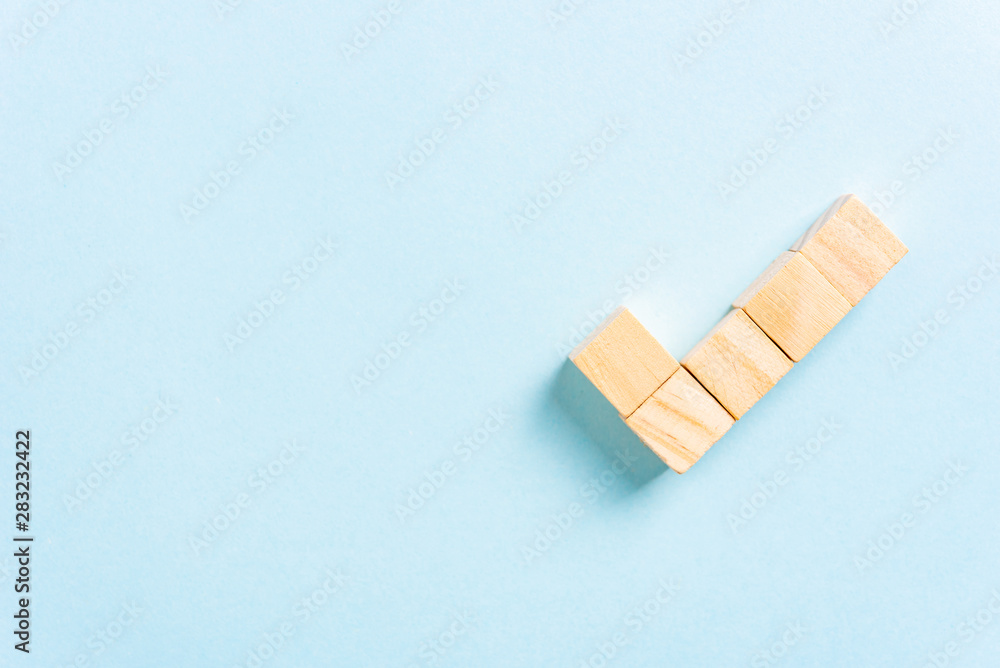 Check mark made with wooden block toys on blue background with blank ...