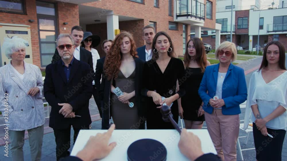 Close-up auctioneer calling out a bid from business lady at auction ...