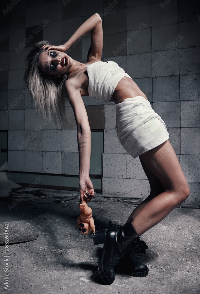 Weird mad girl with scary ugly doll in forsaken place (asylum). Crazy ...