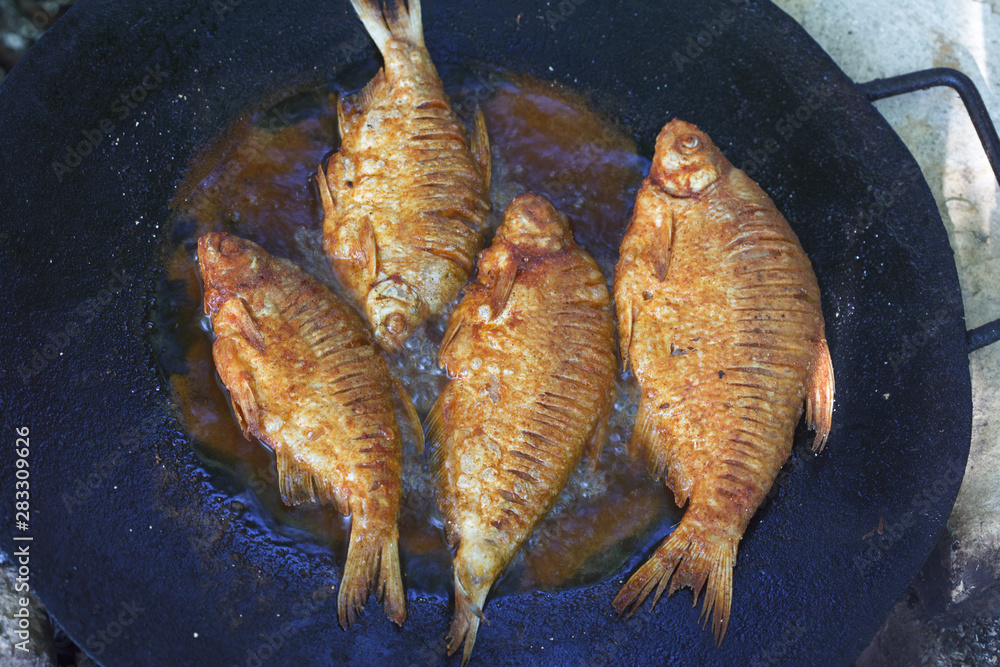 Frying carp fish in a frying pan on an open fire. Cooking fish for ...