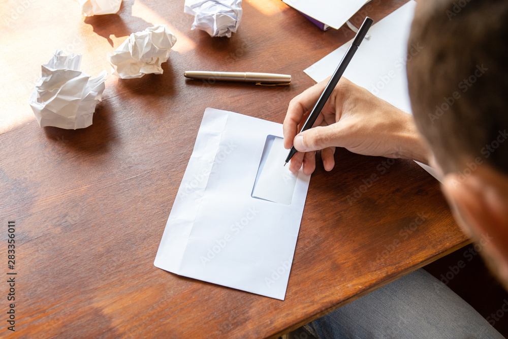 handwritten man signs a mail envelope Stock Photo | Adobe Stock