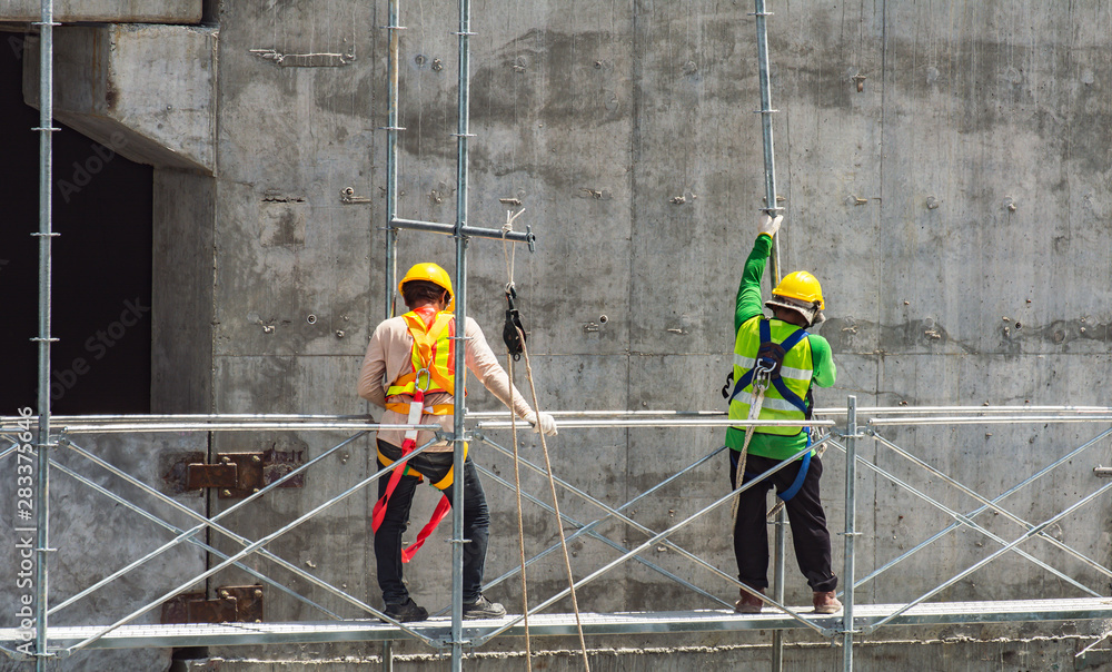 Construction worker wearing safety work at high uniform on scaffolding ...