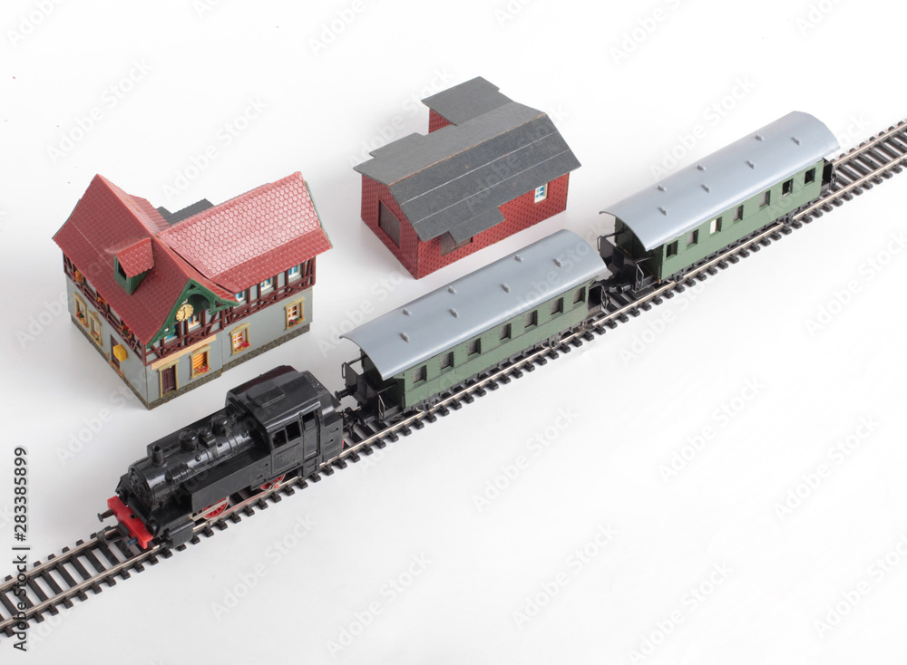 Model of a steam locomotive and passenger cars on rails on a white ...