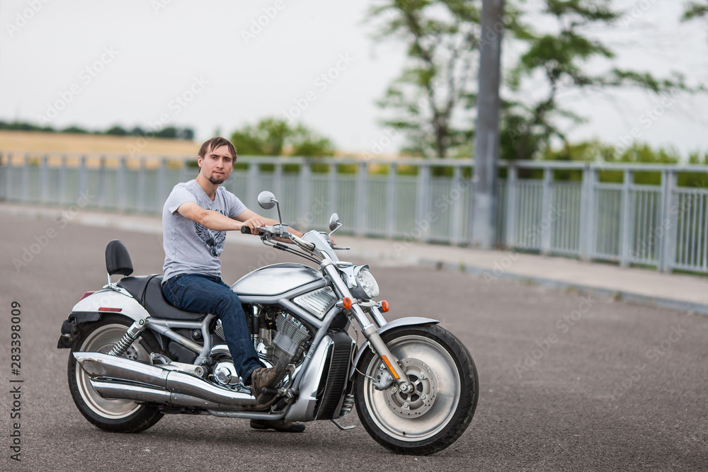 Handsome rider man sitting on classic style cruiser motorbike on an ...