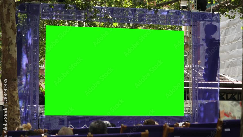 Big Green Screen Display Cinema Outdoors. People sitting on chairs and ...