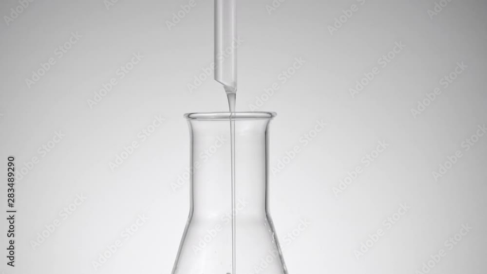 Clear liquid dripping down from lab test tube to a glass beaker, clean ...