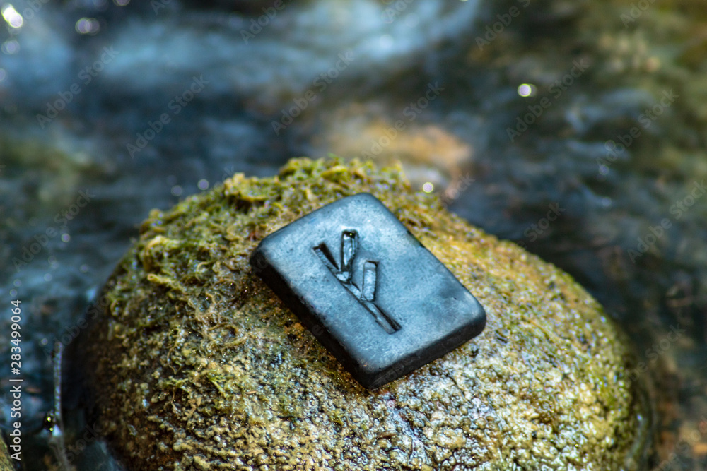 Norse rune Fehu on the stone and the evening river background. Wealth ...